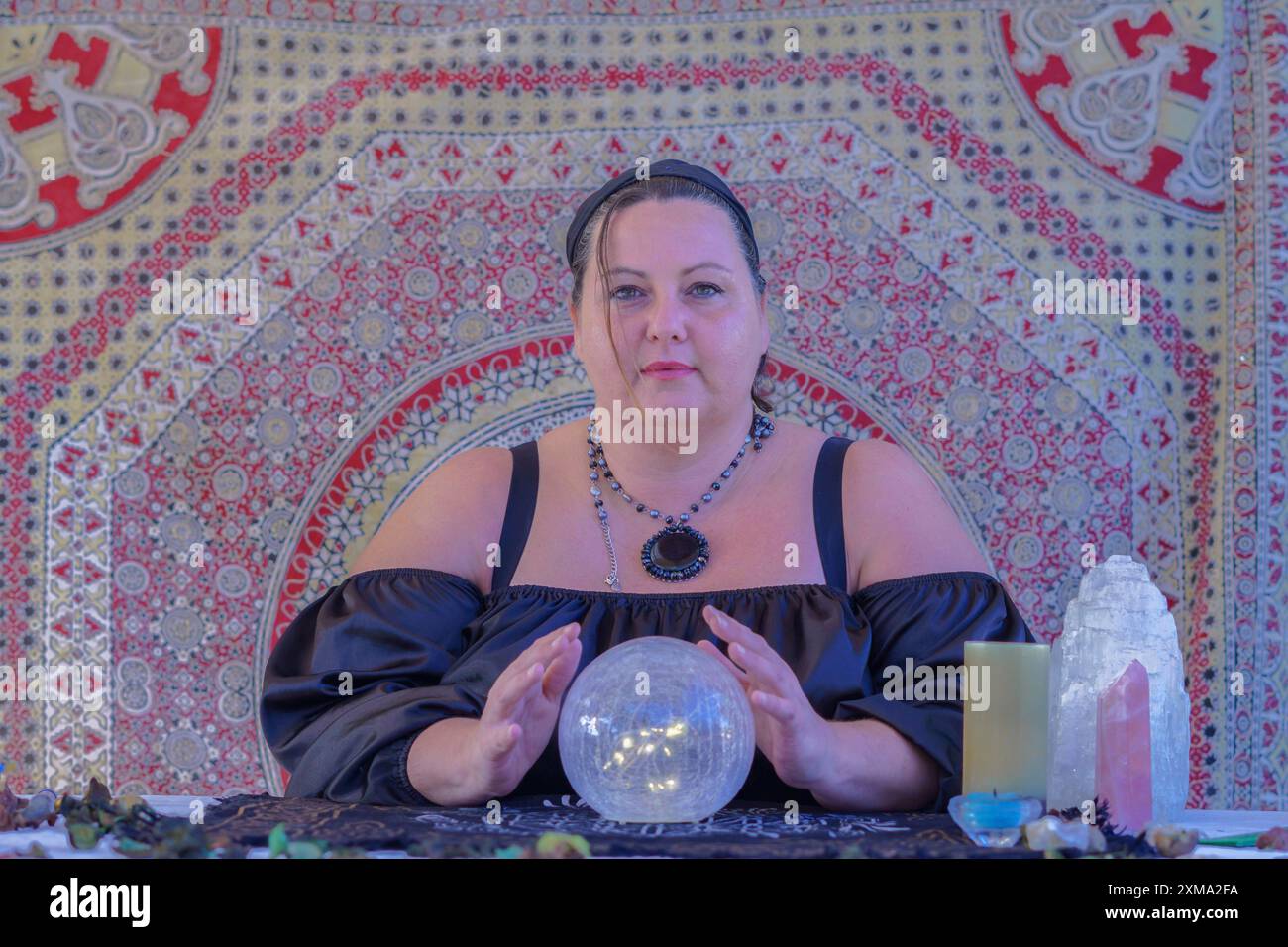 A woman fortune teller dressed in black reads the future in a crystal ...
