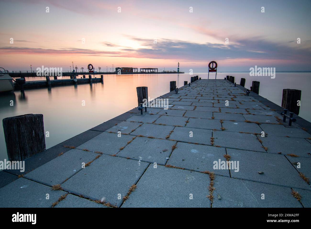Sunrise on the shore and harbour of a lake in summer. Colourful sky ...