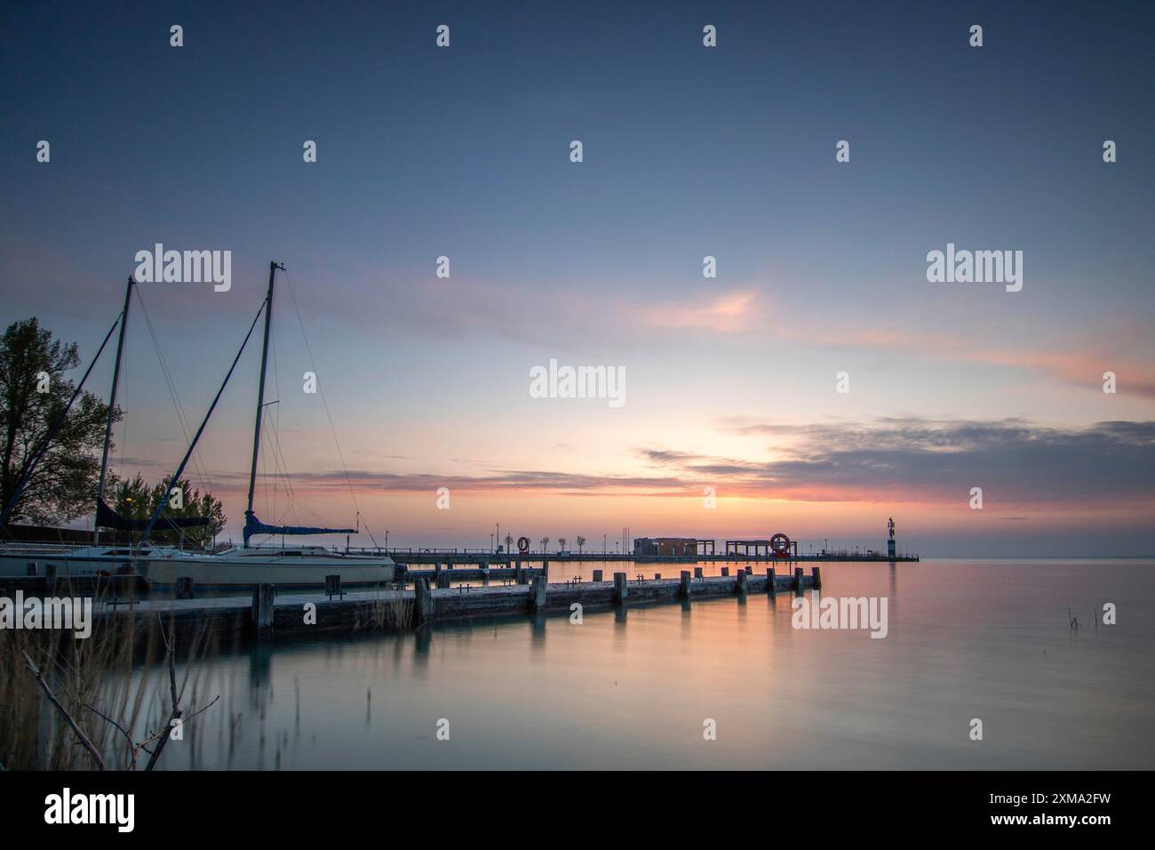 Sunrise on the shore and harbour of a lake in summer. Colourful sky ...