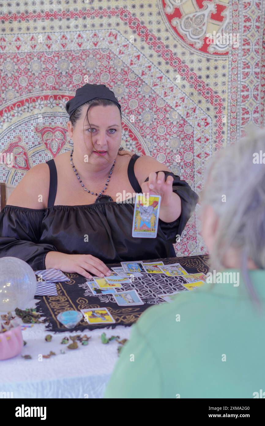Gypsy fortune teller dressed in black showing a tarot card to her ...