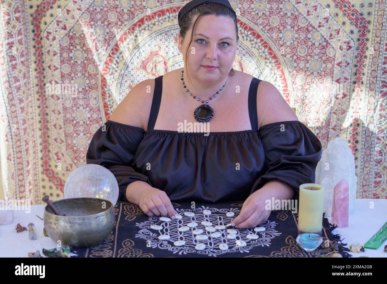 A gypsy fortune teller dressed in black predicts the future with rune ...