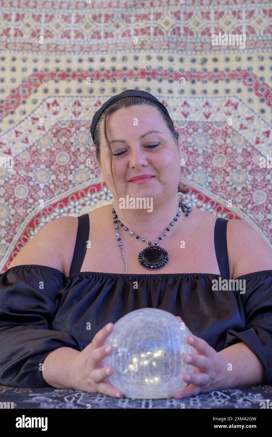 A woman fortune teller dressed in black reads the future in a crystal ...