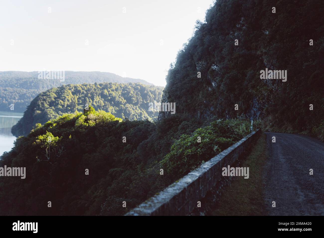 A road runs along a cliff overlooking a lake and wooded hills, Lake ...