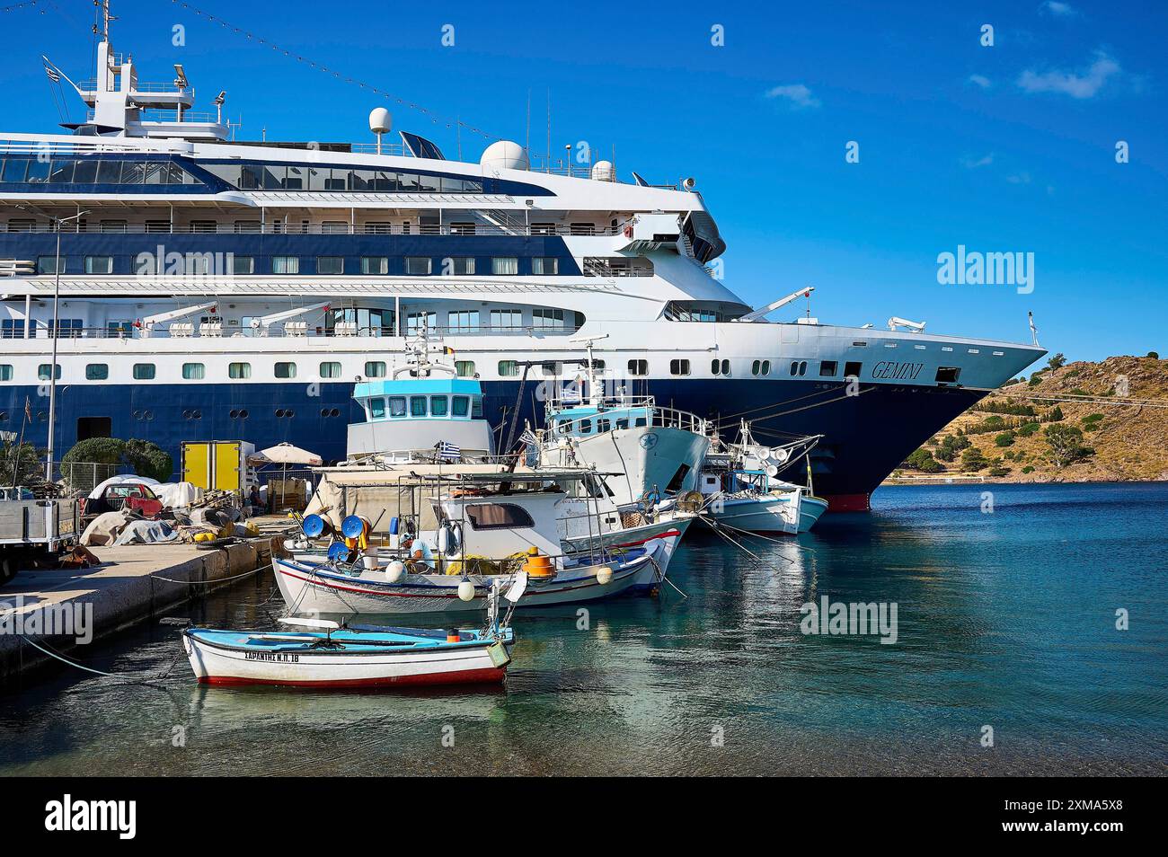 A large cruise ship moored in the harbour of a Greek island, surrounded ...