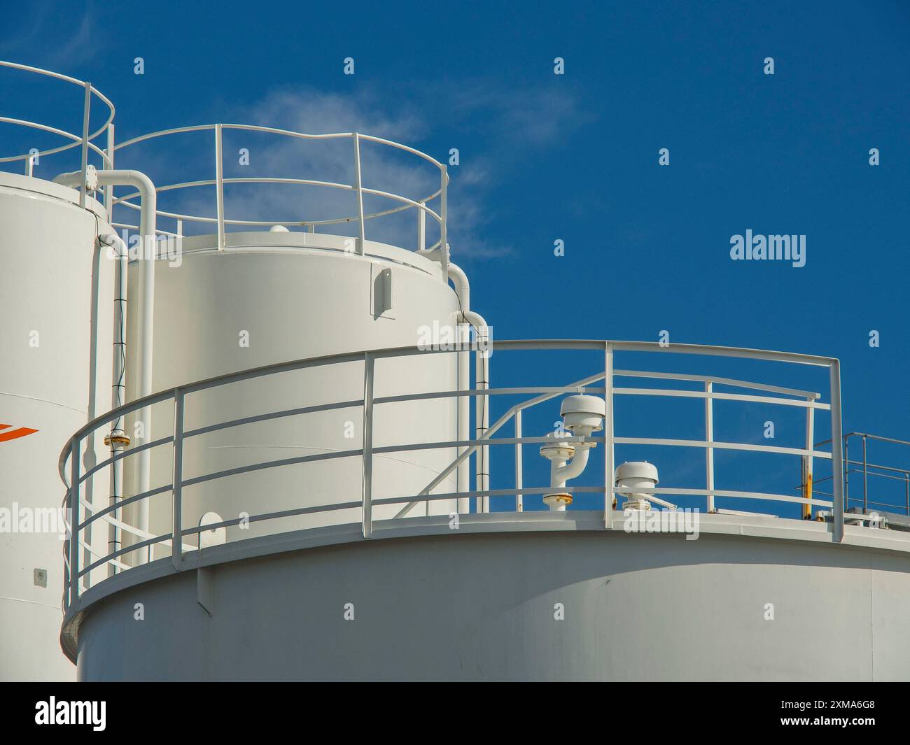 White silos with metal railings under a clear blue sky with few clouds ...