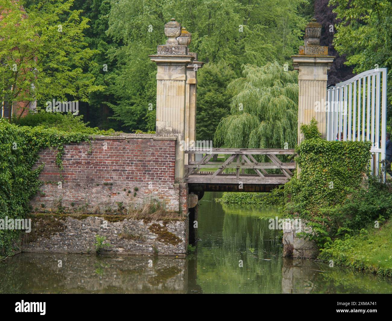 Historic bridge over a moat, surrounded by green trees, Havixebeck ...