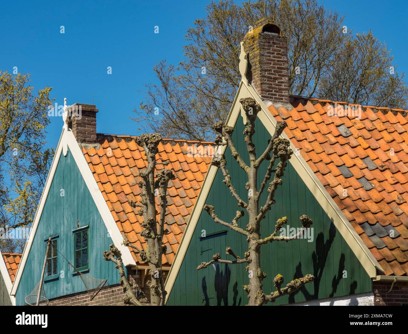 Traditional houses with orange-coloured tiled roofs and green facades ...