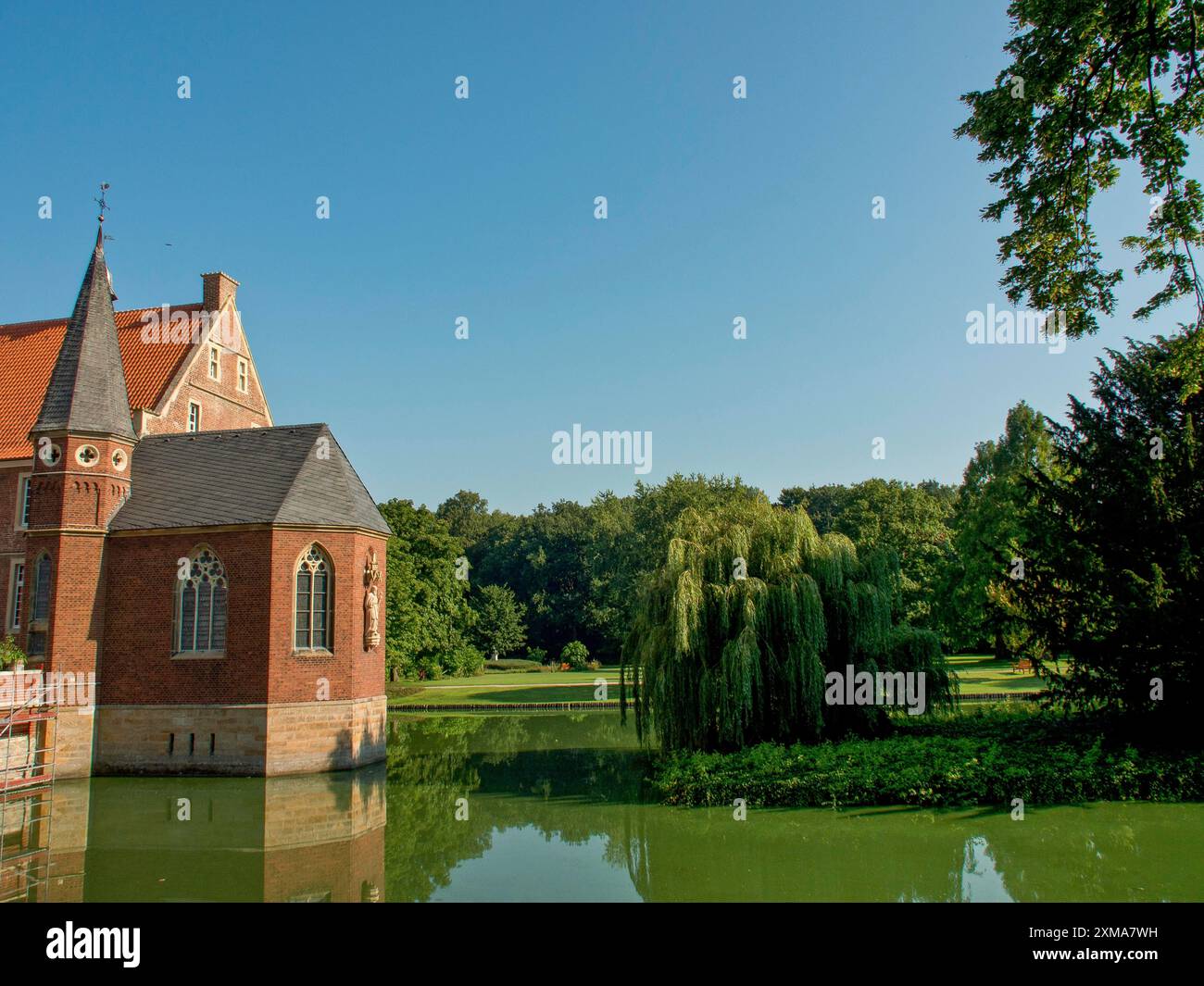 An idyllic castle by a pond, surrounded by trees and blue sky ...