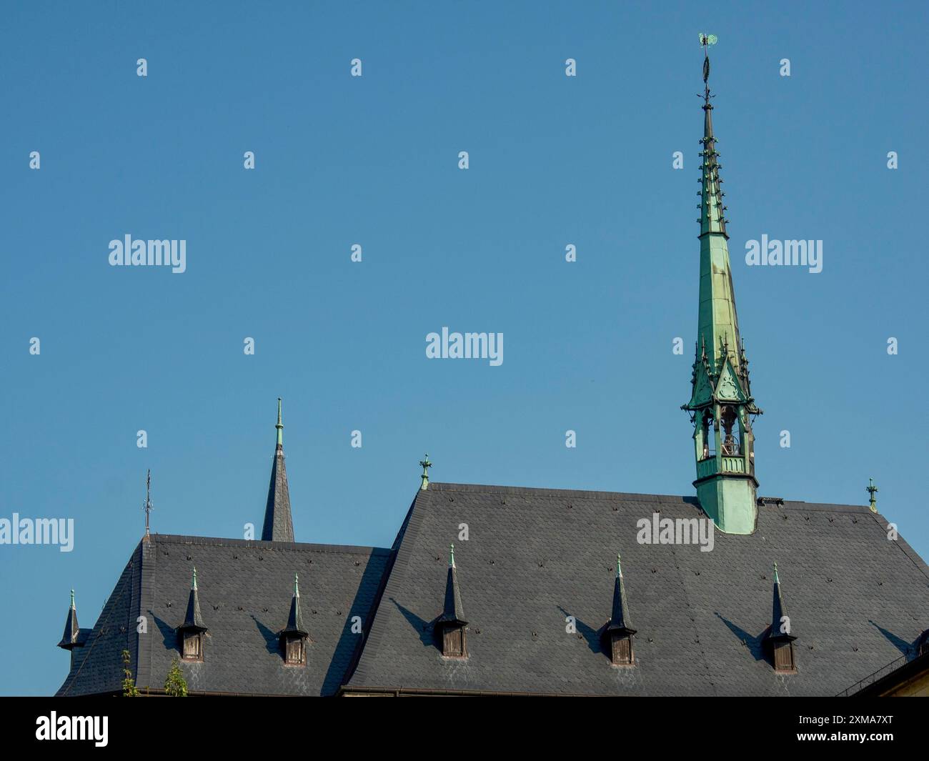 Top of a historic church tower with slate roof under a blue sky ...