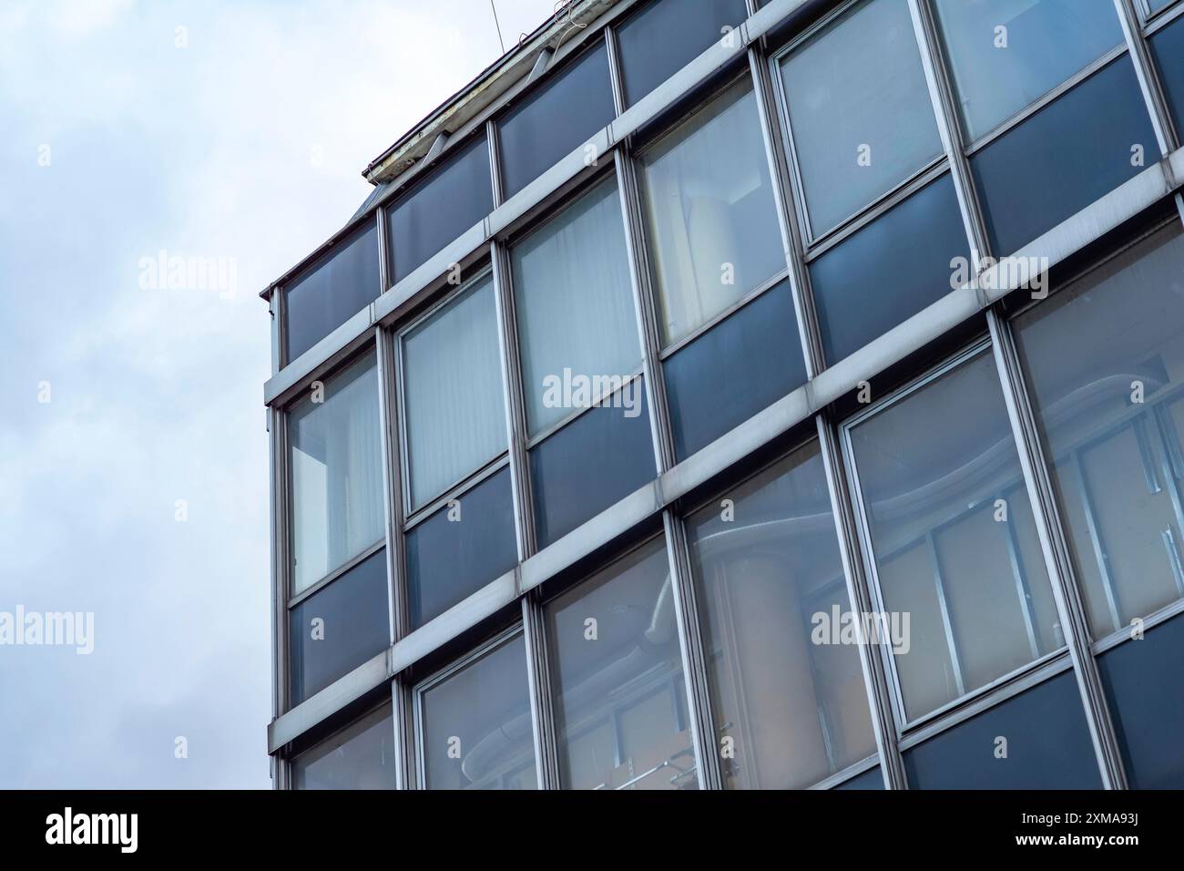 The corner of a building with a glass facade and reflective windows ...
