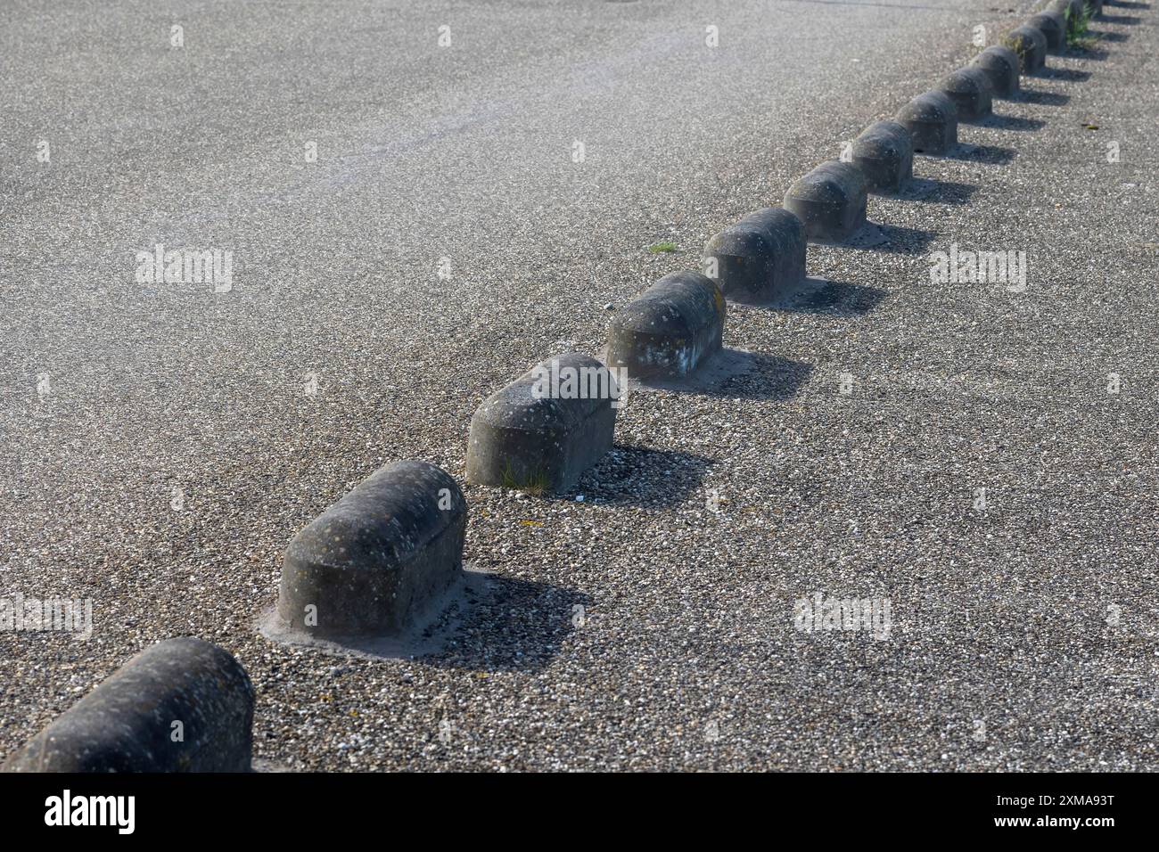 Row of round concrete bollards on the roadside creates a pattern of ...