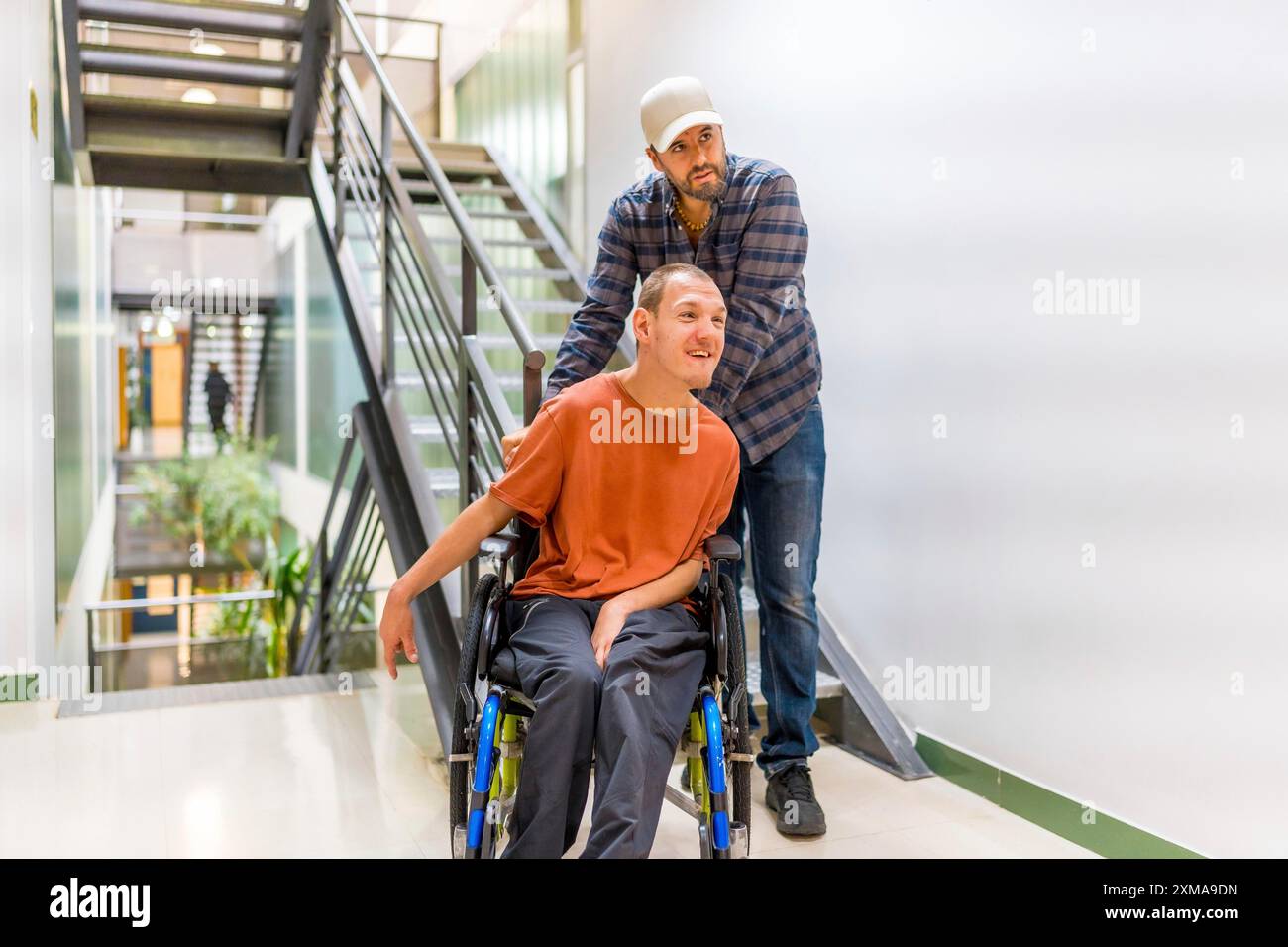Man assisting a coworker with disability walking and pushing his ...