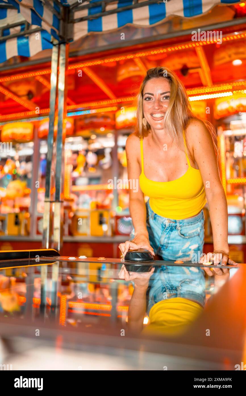 Vertical photo of a happy woman playing air hockey and having fun in an ...