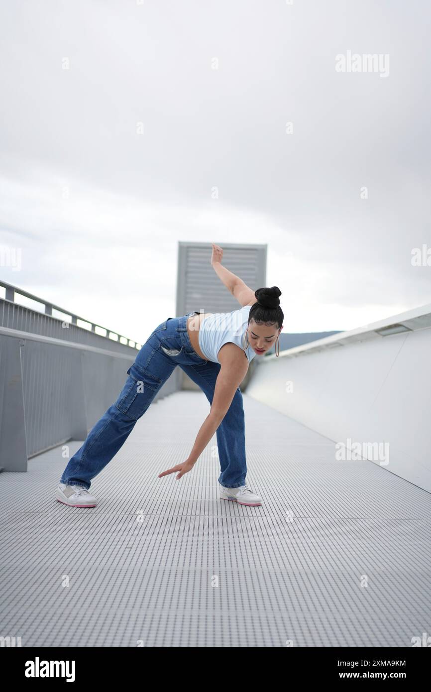 A woman is doing a dance on a white ledge. She is wearing blue jeans ...