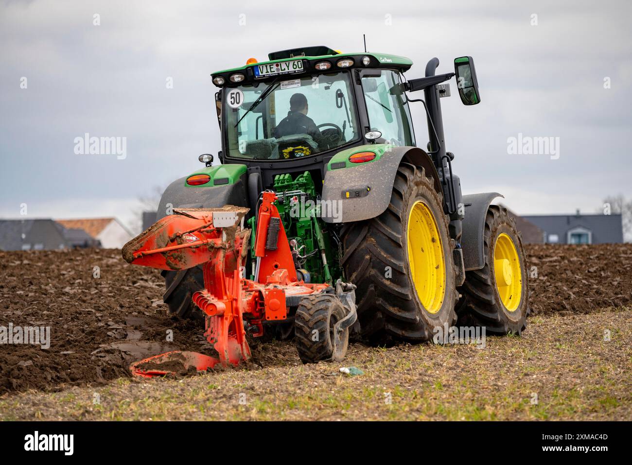 Tractor with a plough preparing the soil of a field for planting ...