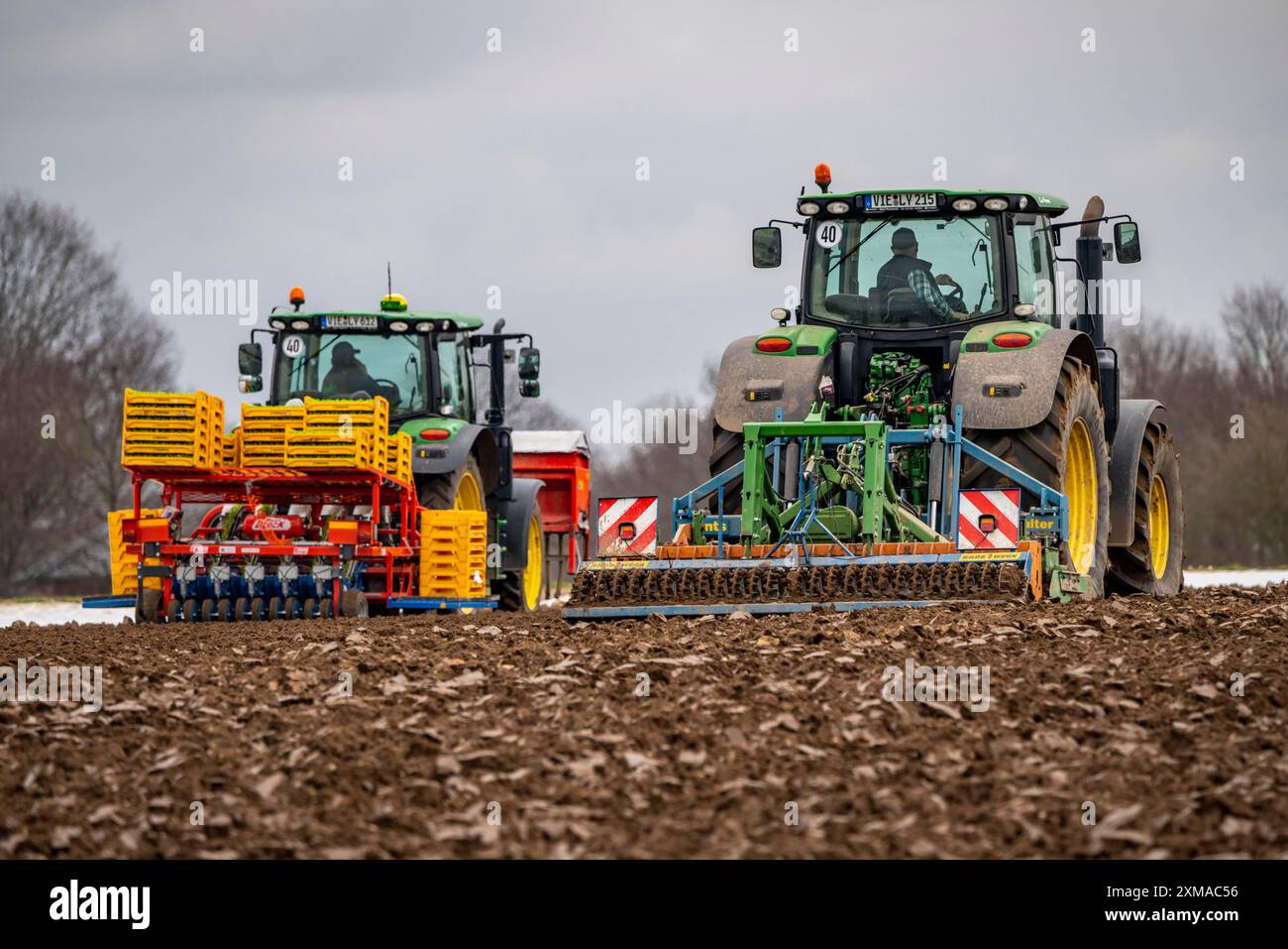 Tractor with a power harrow prepares the soil of a field for planting ...