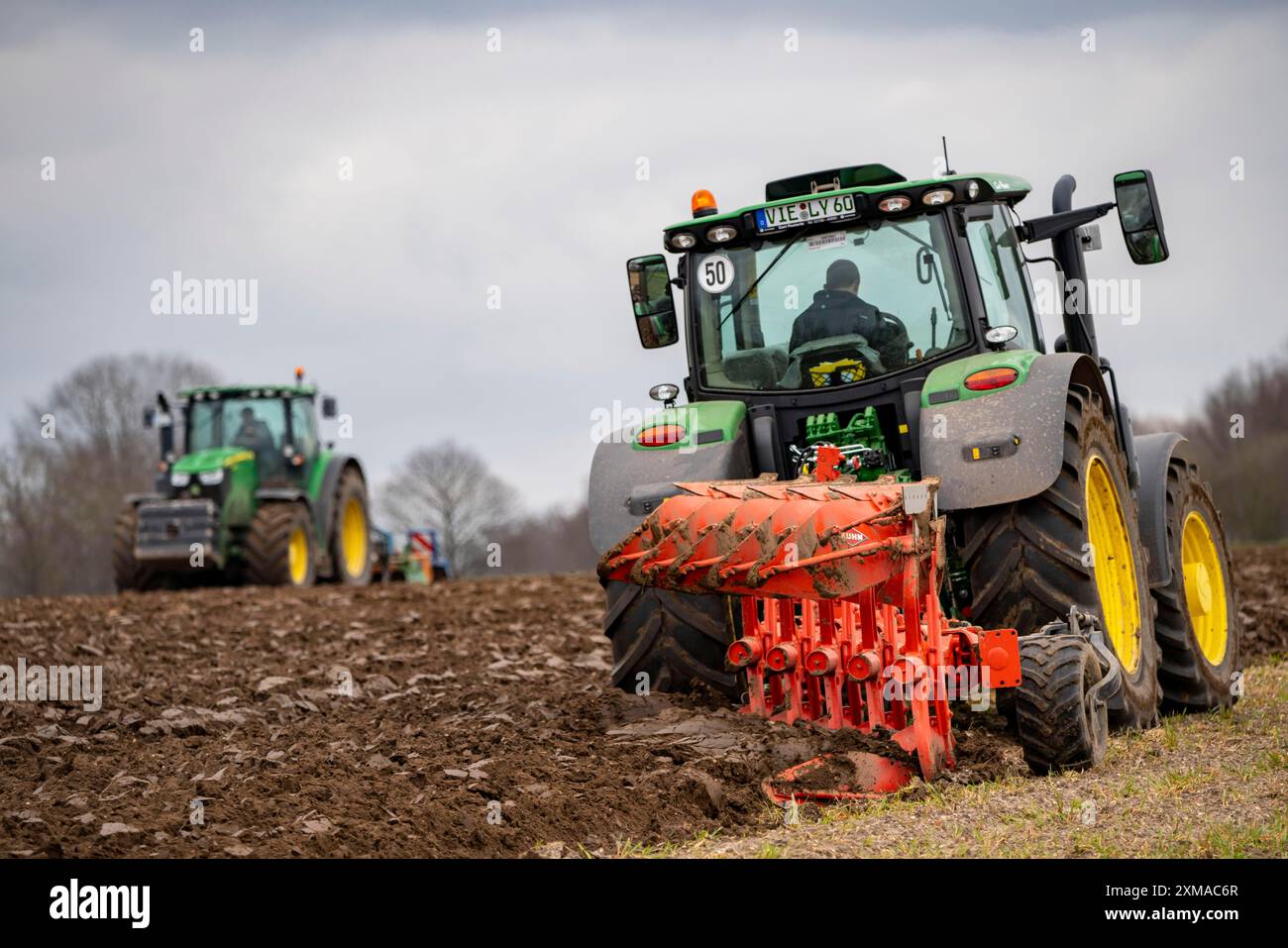 Tractor with a plough preparing the soil of a field for planting ...