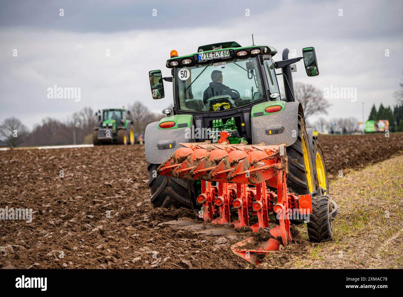 Tractor with a plough preparing the soil of a field for planting ...