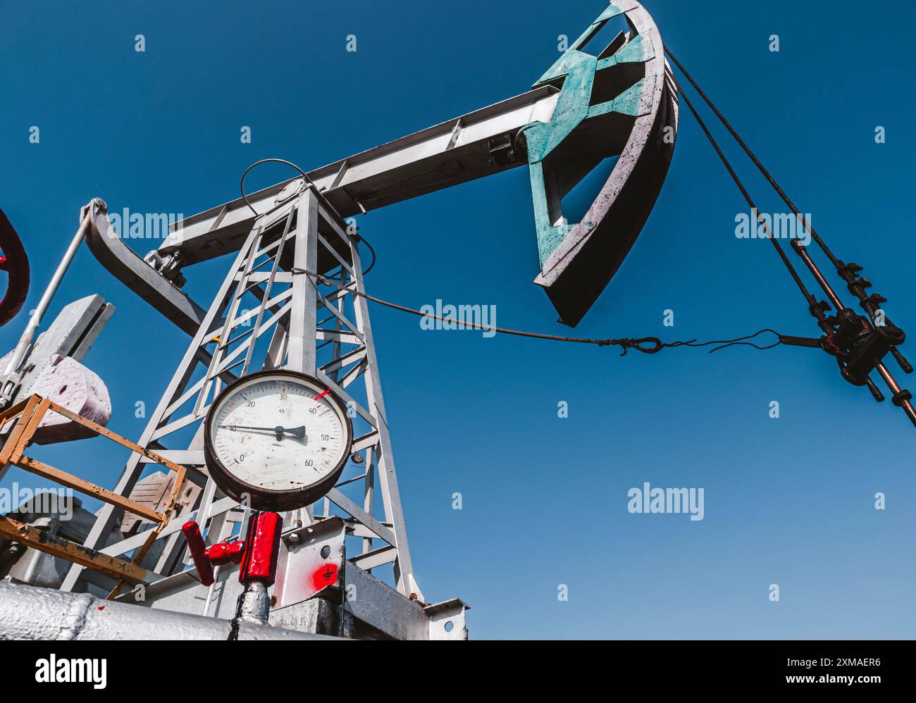 Oil pump jack operating under clear blue sky at oil field during ...