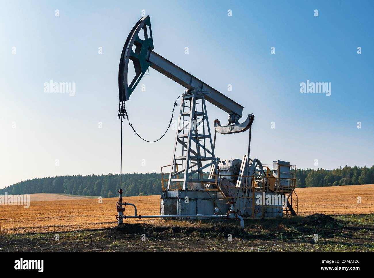 An oil pumpjack is actively extracting crude oil from beneath the earth ...
