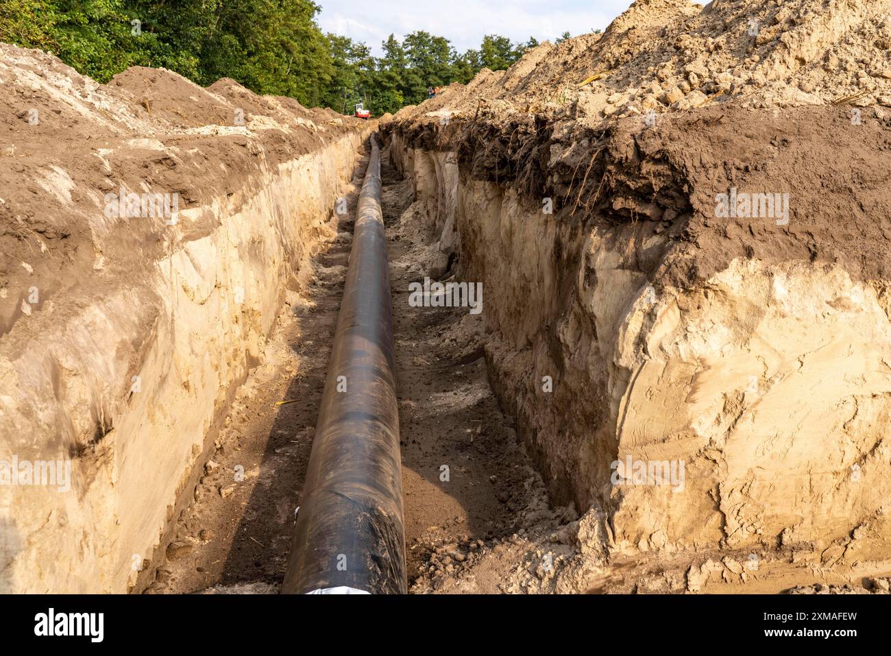 Laying of district heating pipes, next to a field, with maize, the district heating comes from a ...