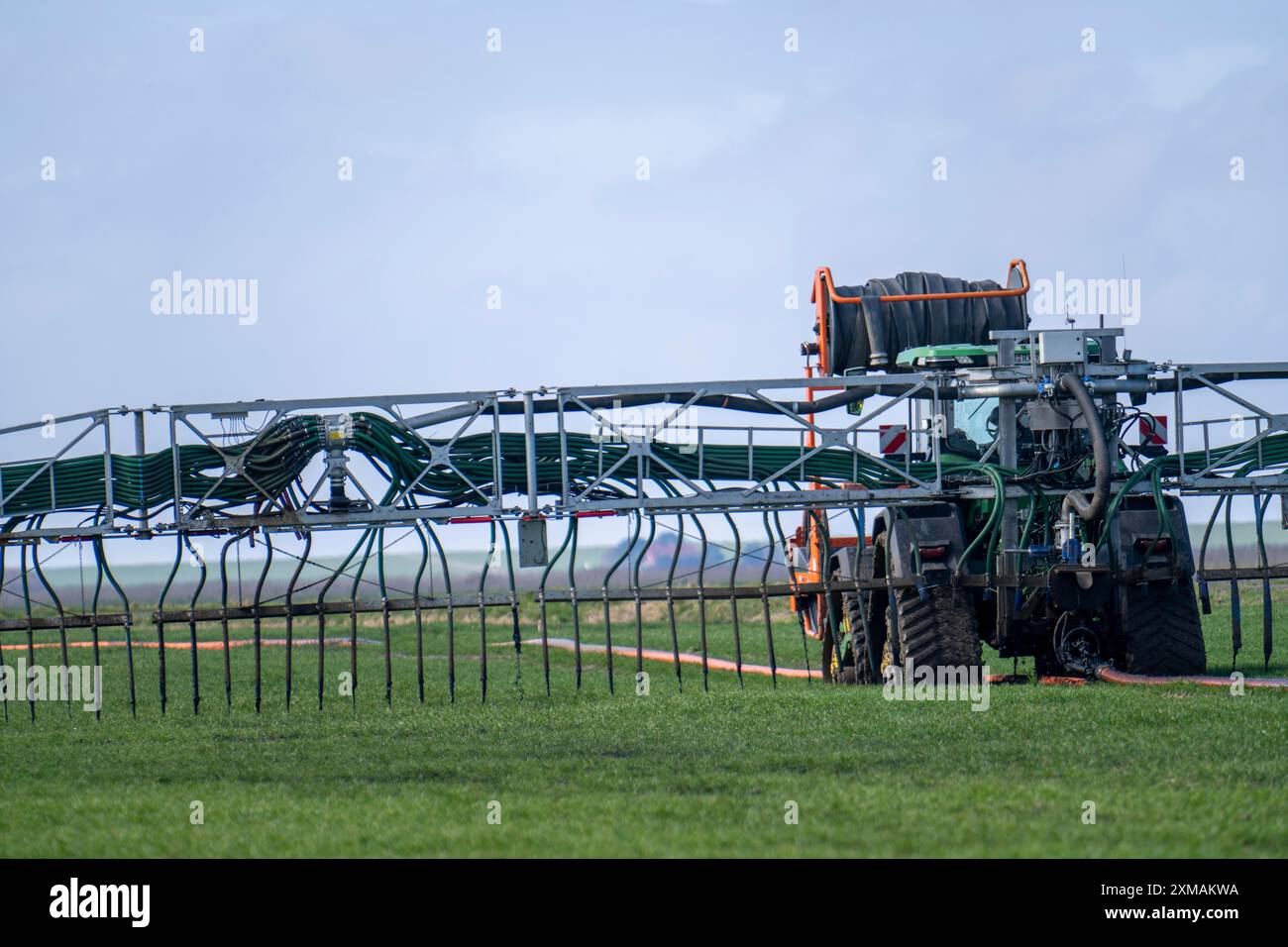 Tractor with boom for spreading liquid manure, on a field ...