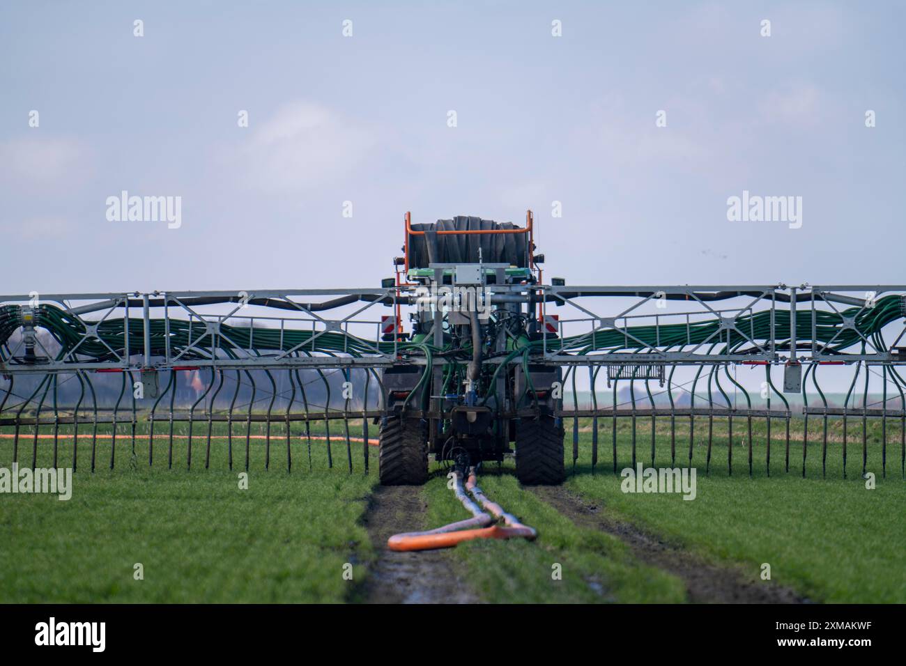 Tractor with boom for spreading liquid manure, on a field ...