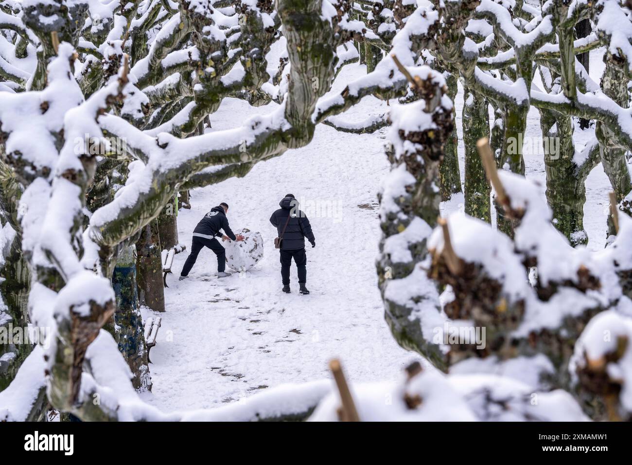 Winter in the city, southern Main promenade, 2 men forming a snow globe ...