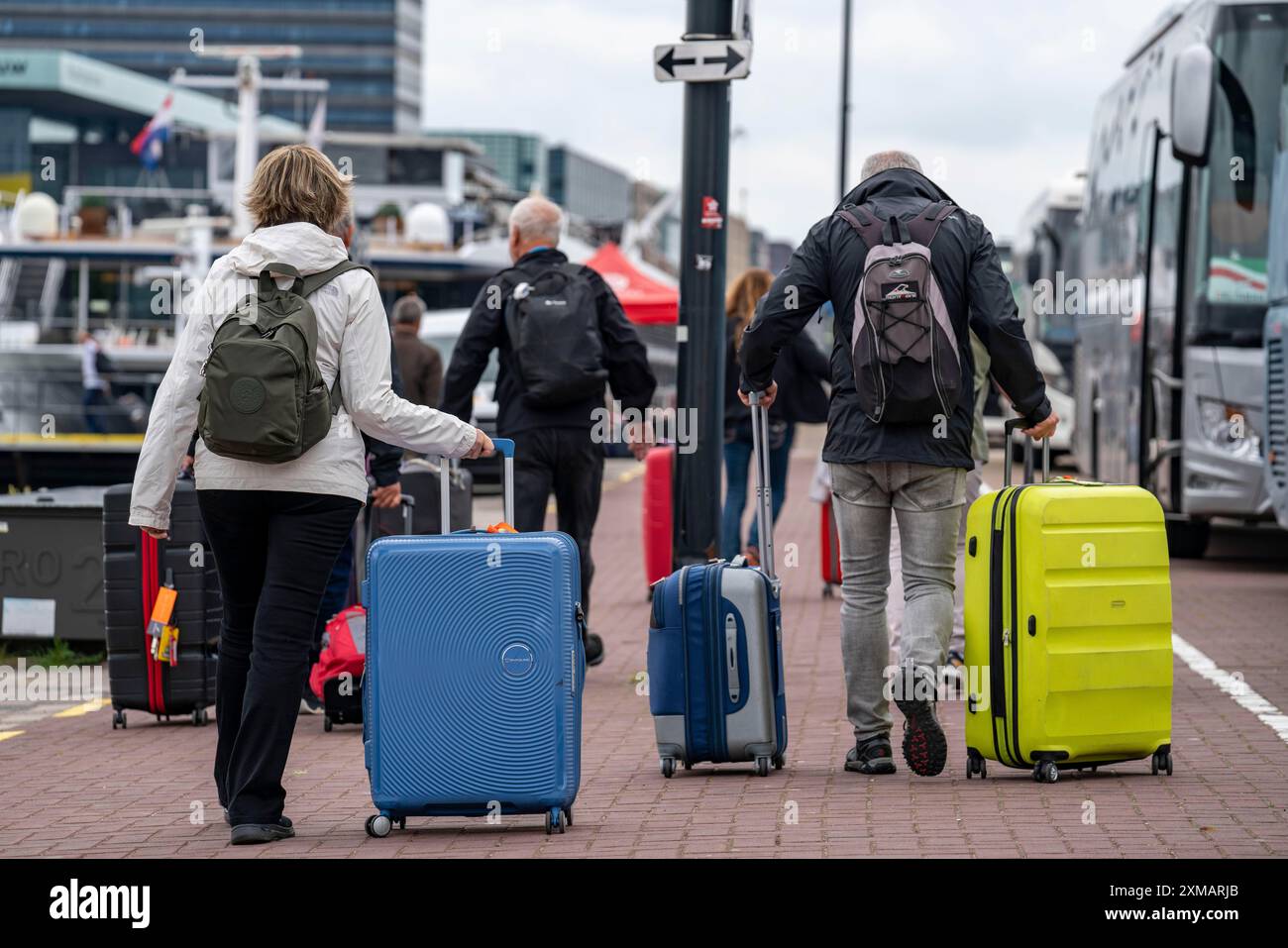 Travellers on their way to a river cruise ship at the quay of the Ij ...