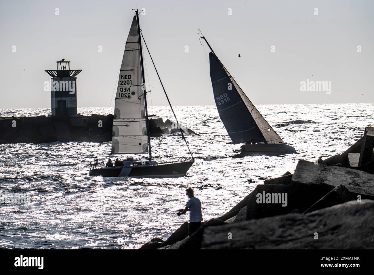 Sailing boat leaving the harbour of Scheveningen, lighthouse at the ...