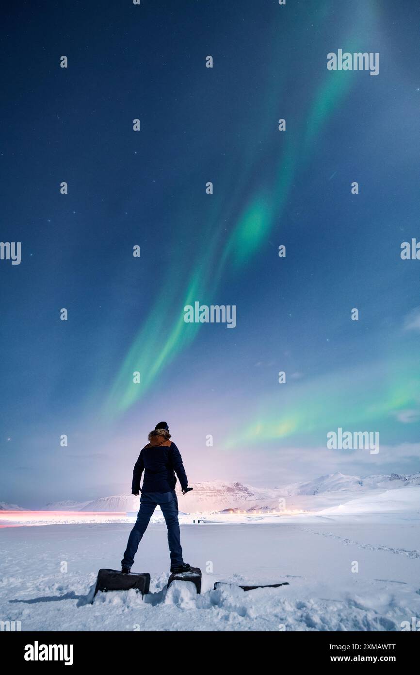 Lone man hiker gazing at the Aurora Borealis Northern Lights in awe in ...