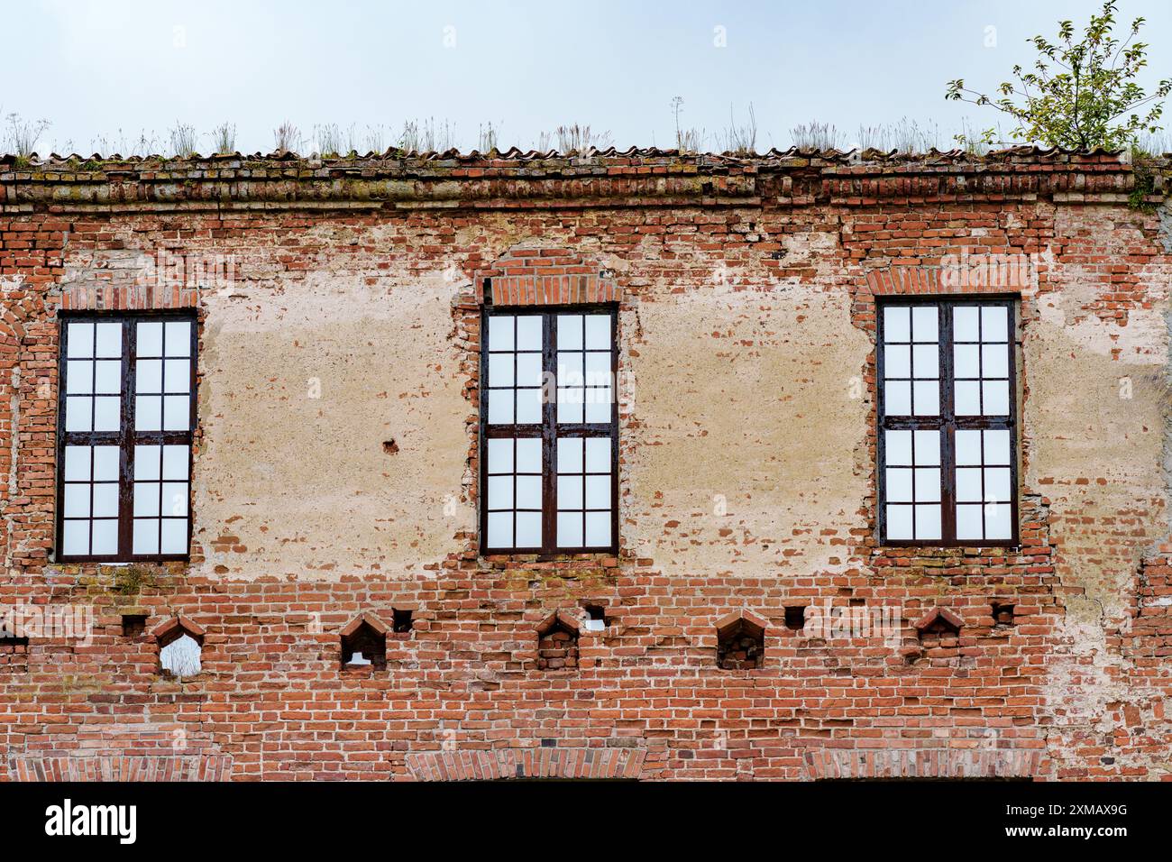 An abandoned, aged brick building with broken windows. The walls ...