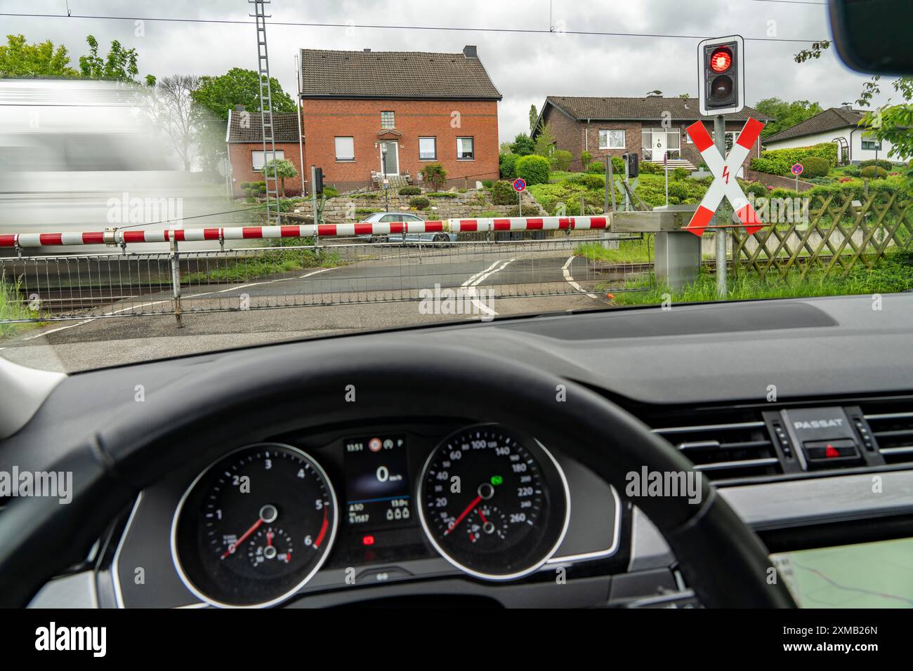 Car waiting at a level crossing, closed barriers, red warning light ...