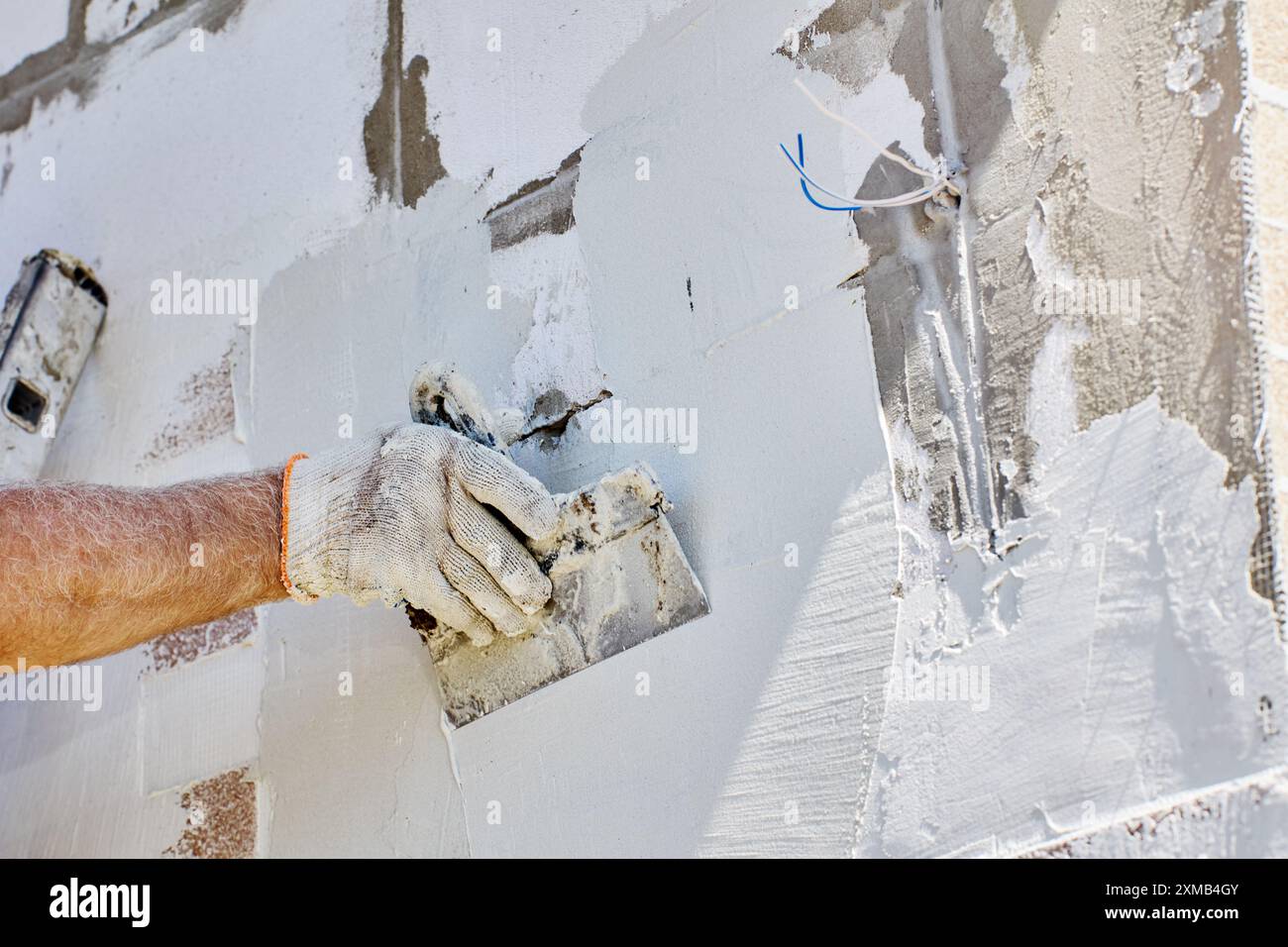 Applying tile adhesive to facade of building, house painter uses steel ...