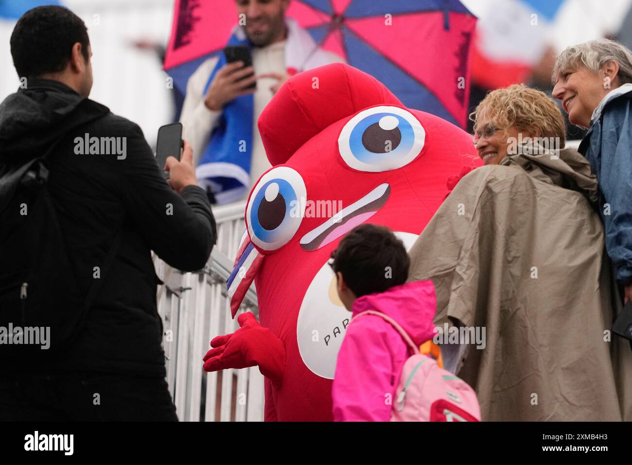 Spectators pose with the Olympic Phryge, the mascot, ahead of rowing ...