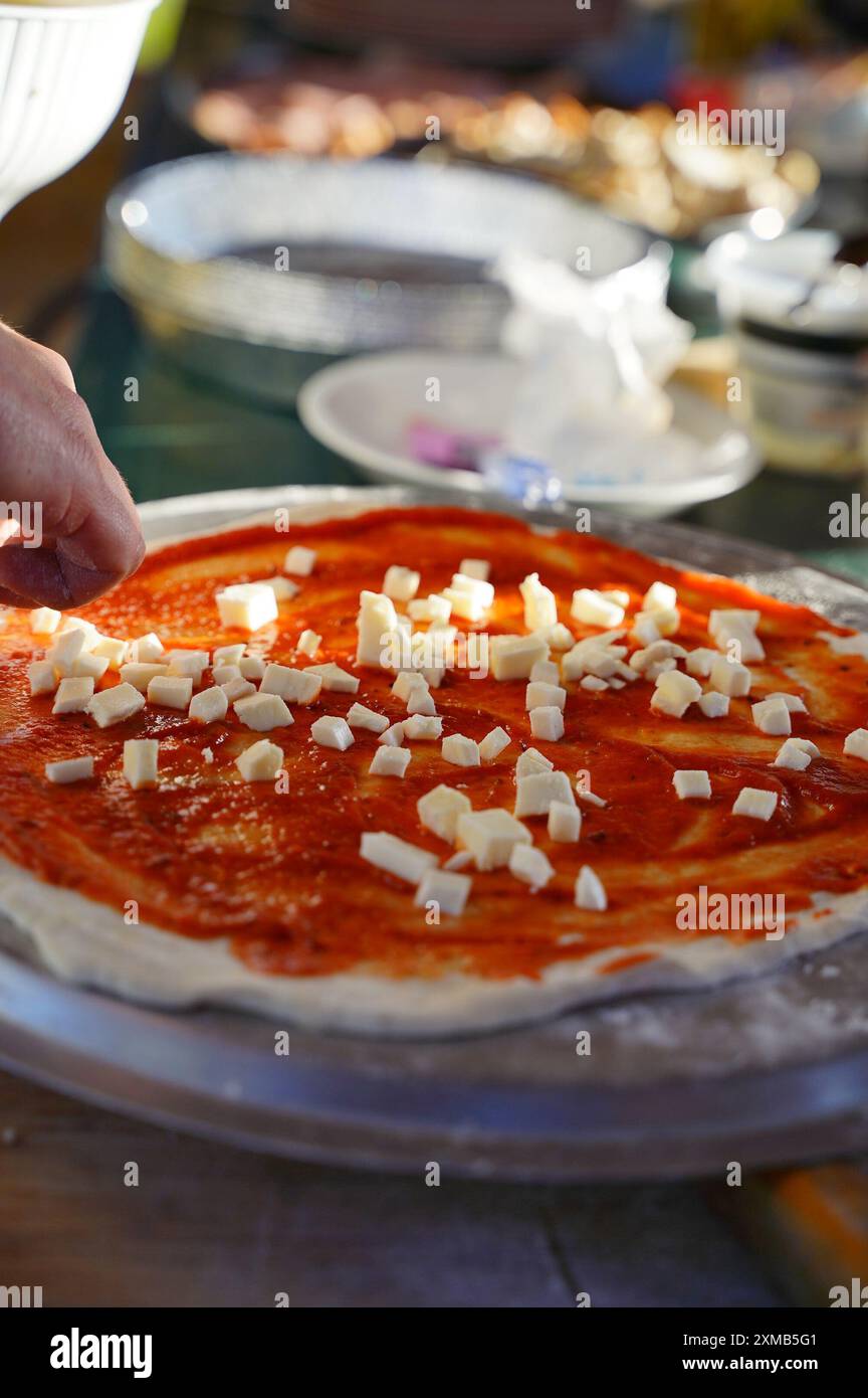 Man's hands adding mozzarella cheese to a traditional margarita pizza ...