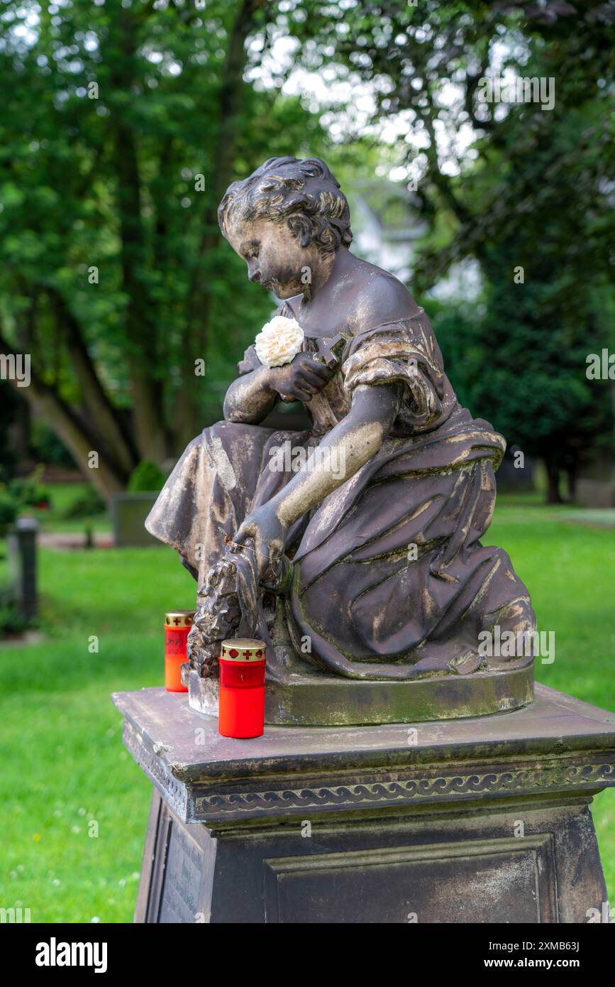 Figure in a cemetery, old gravestone, with flower and grave light ...