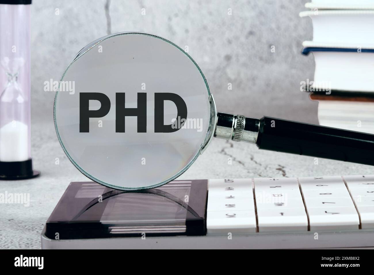 The word PHD is written appeared through a magnifying glass on a gray ...