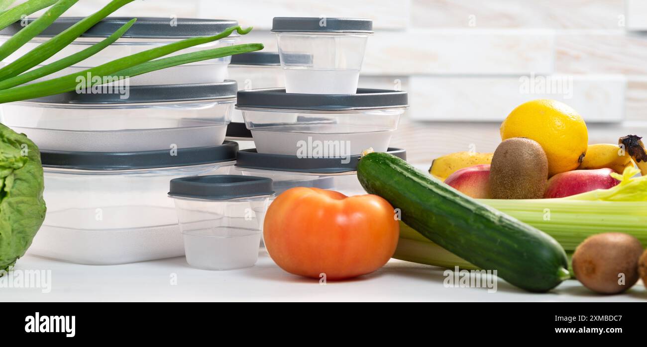 A stack of plastic containers and raw vegetables on the table. Storage ...