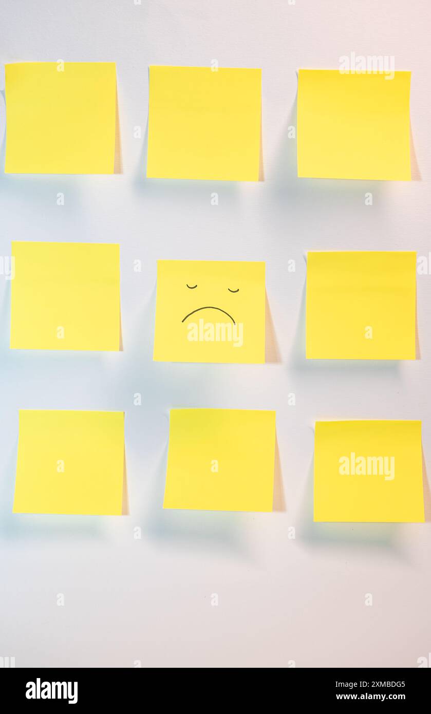 Nine yellow papers and in the center one with a sad face surrounded by ...