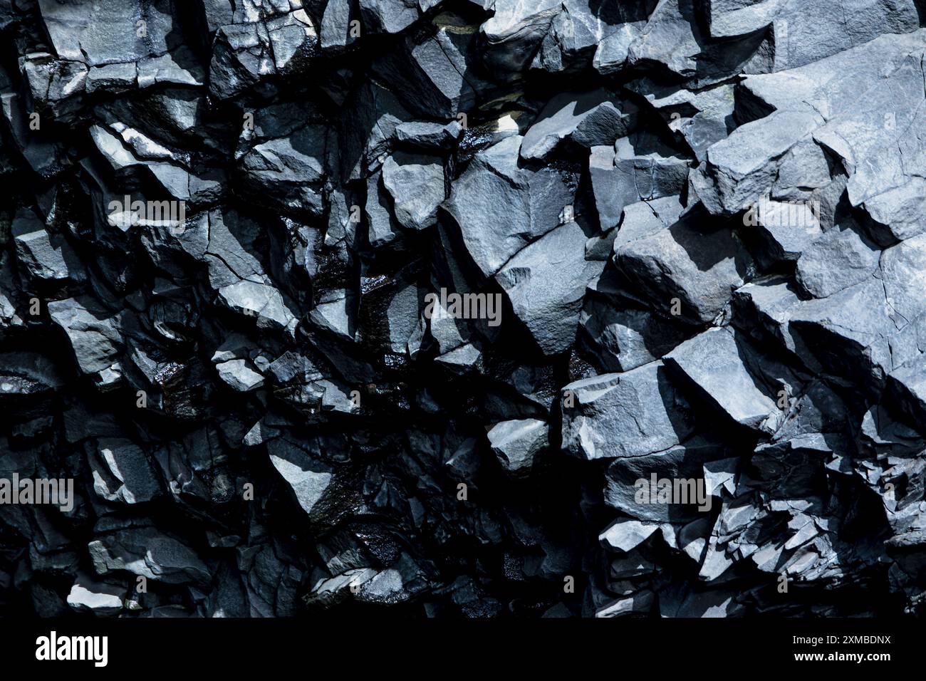 The image is a close up of a rock wall with a black and gray color ...