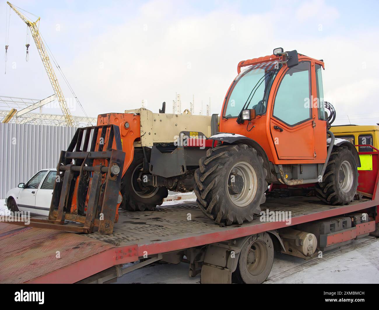 Heavy-duty orange forklift loaded onto a flatbed truck for transport at ...