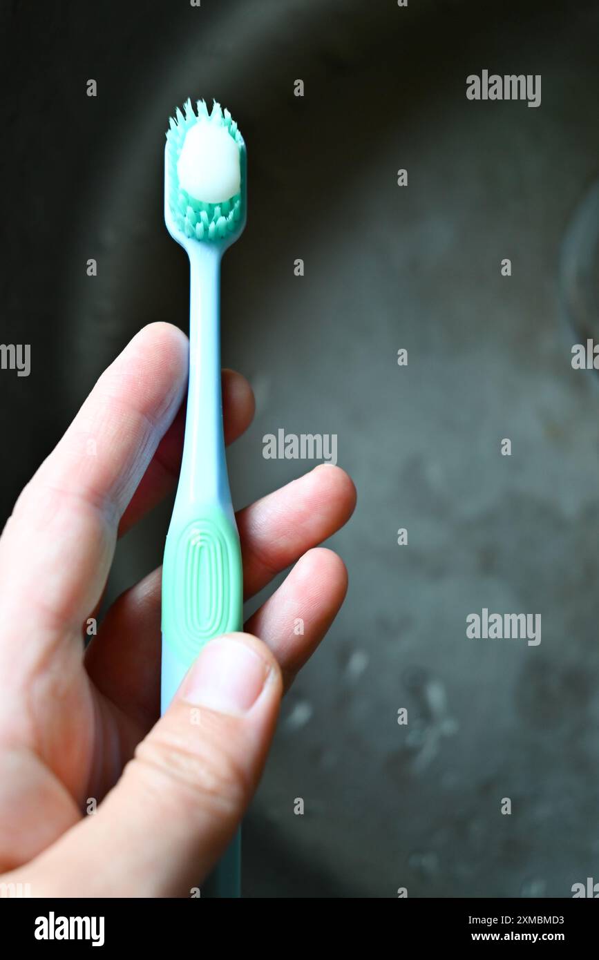 a person is holding a toothbrush with a blue bristles Stock Photo - Alamy