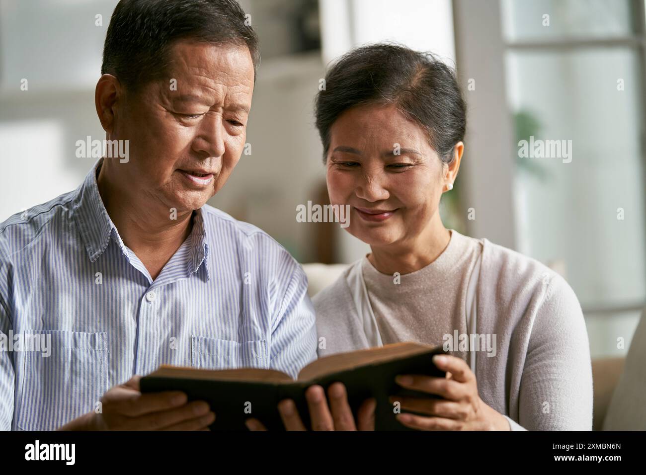 happy senior asian couple sitting on family couch at home reading bible together Stock Photo - Alamy