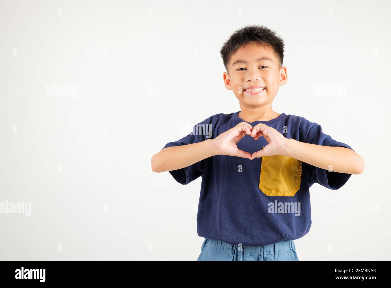 A smiling Asian young kid boy shows confidence, creating a heart shape ...