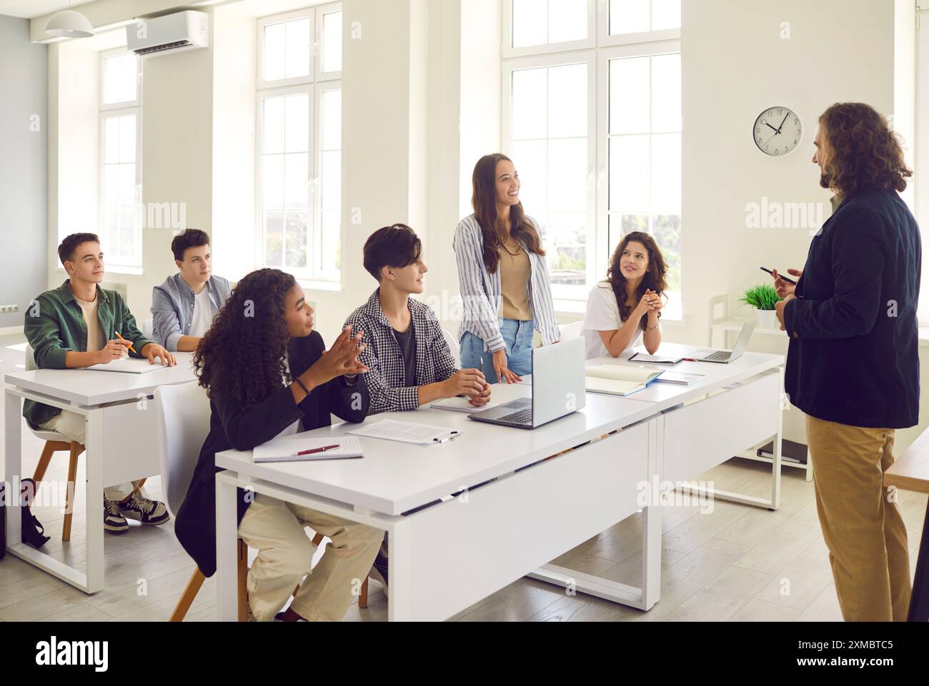 Young girl student standing at the desk in classroom and answering the ...