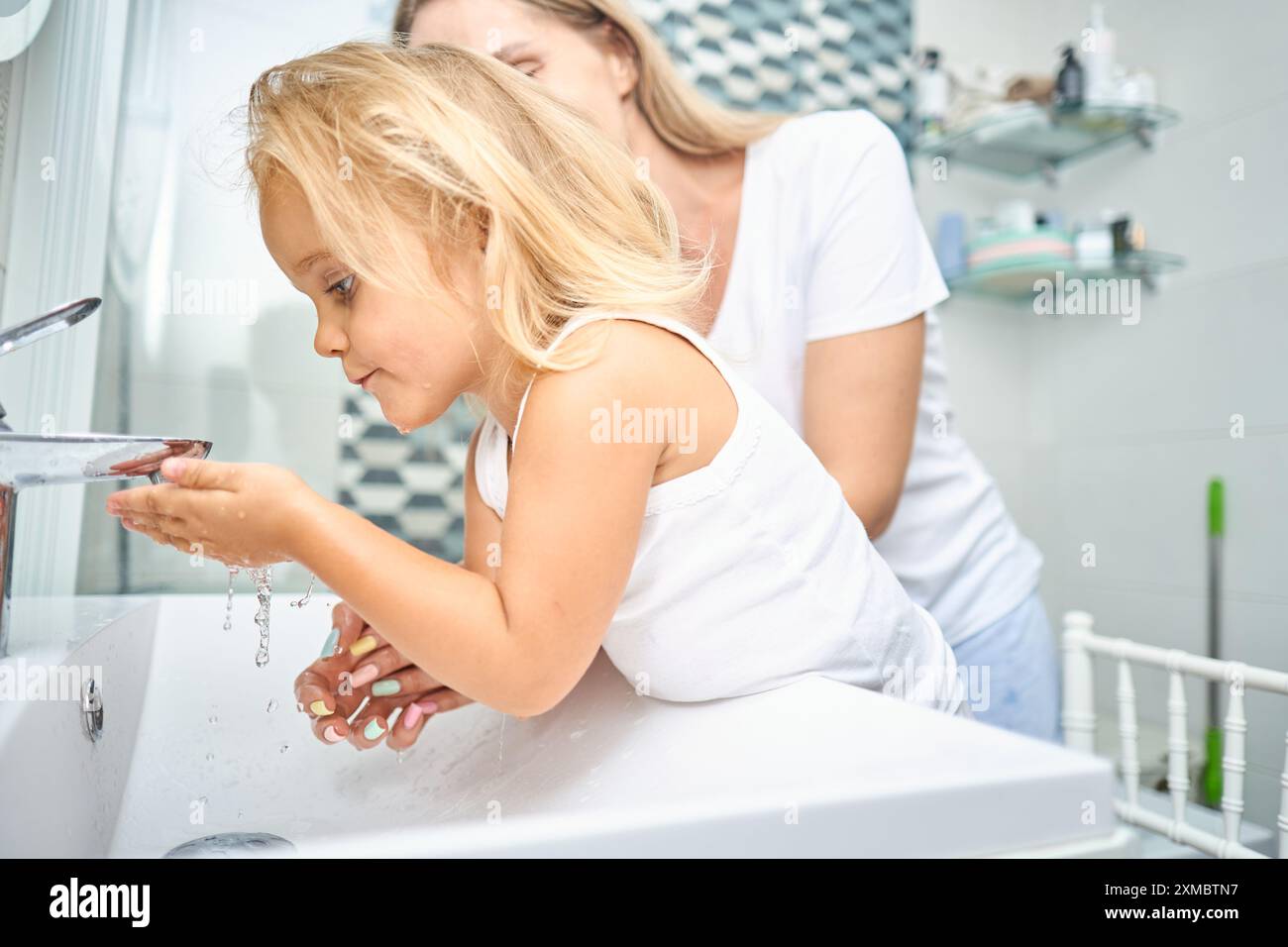 A mother and child washing their faces together in the bathroom in the ...