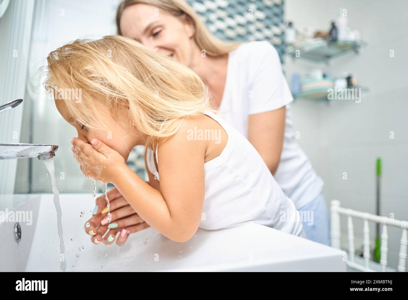 A mother and child washing their faces together in the bathroom in the ...