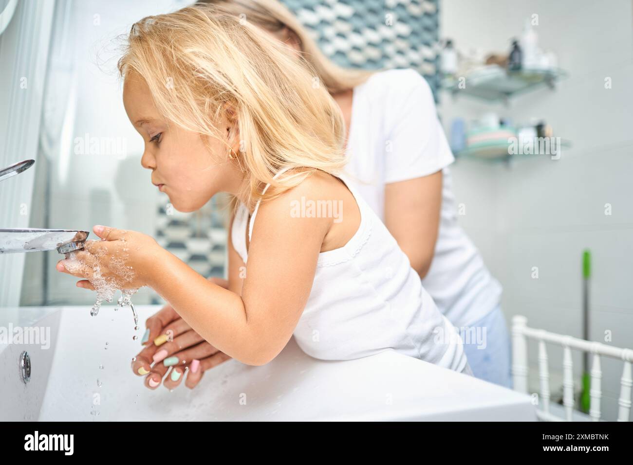 A mother and child washing their faces together in the bathroom in the ...