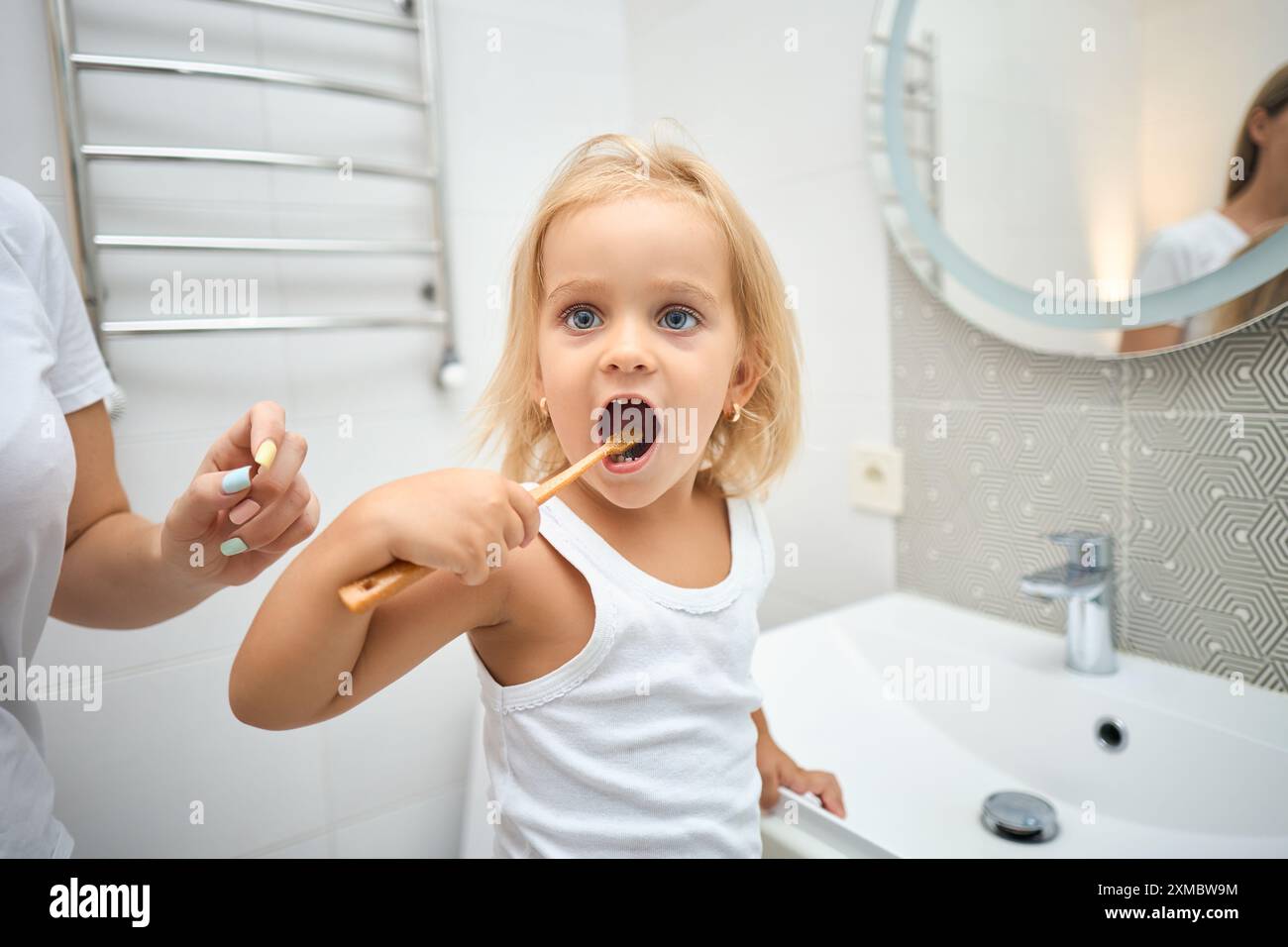 Morning routine, smiling happy child brushing teeth with toothbrush ...